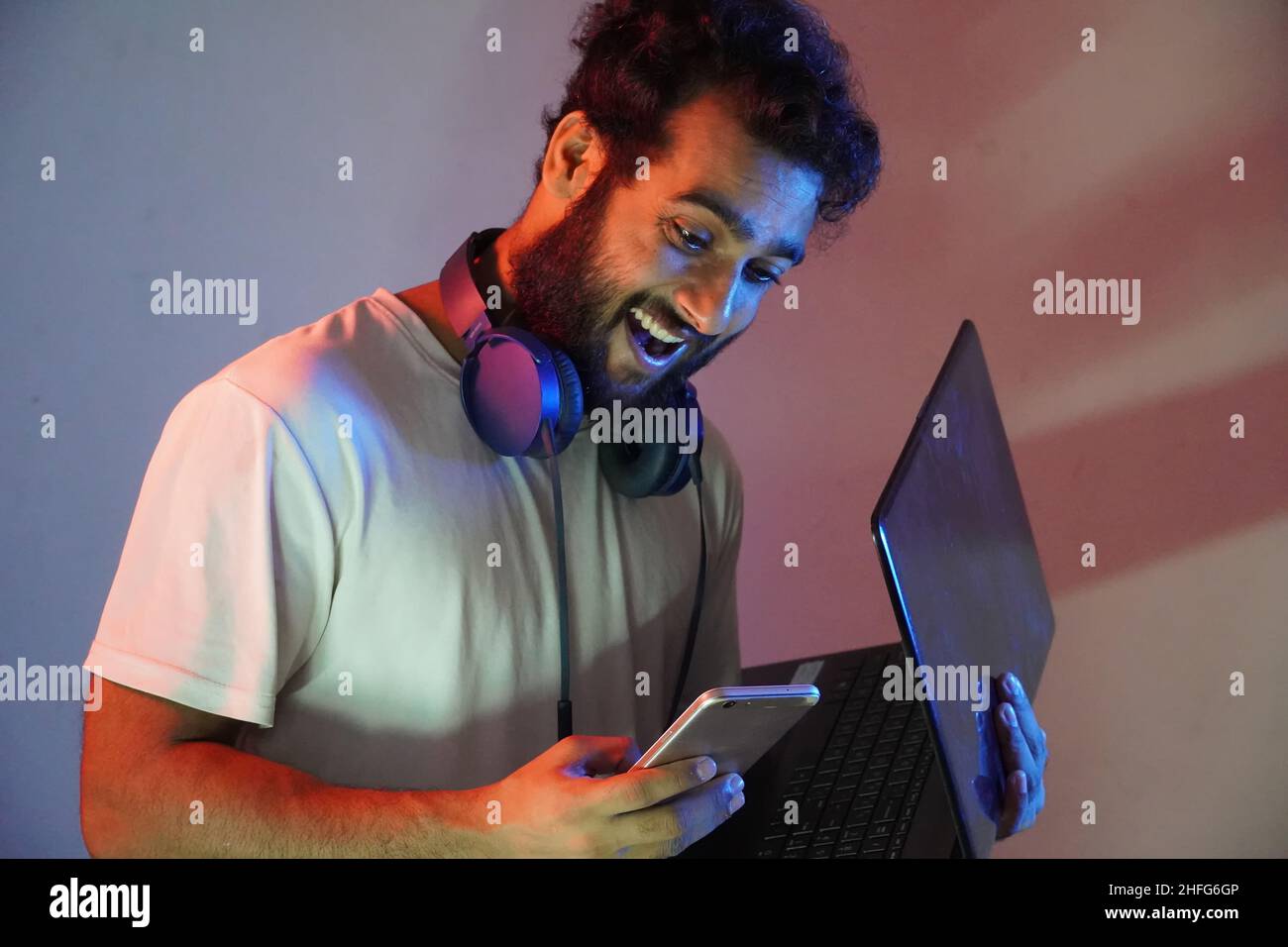 a man in studio with blue and red light having laptop and mobile Stock ...