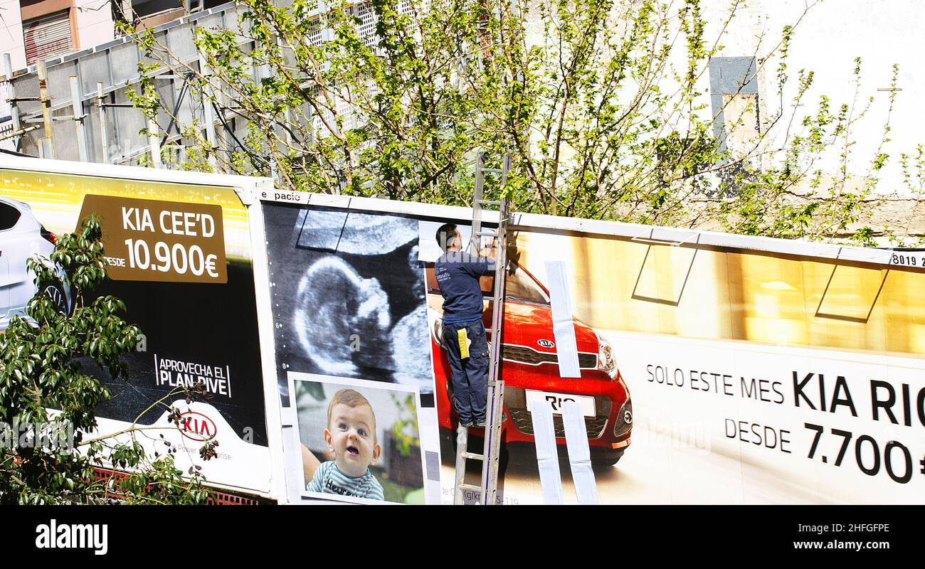 Man placing advertising poster on an advertising billboard in Barcelona ...