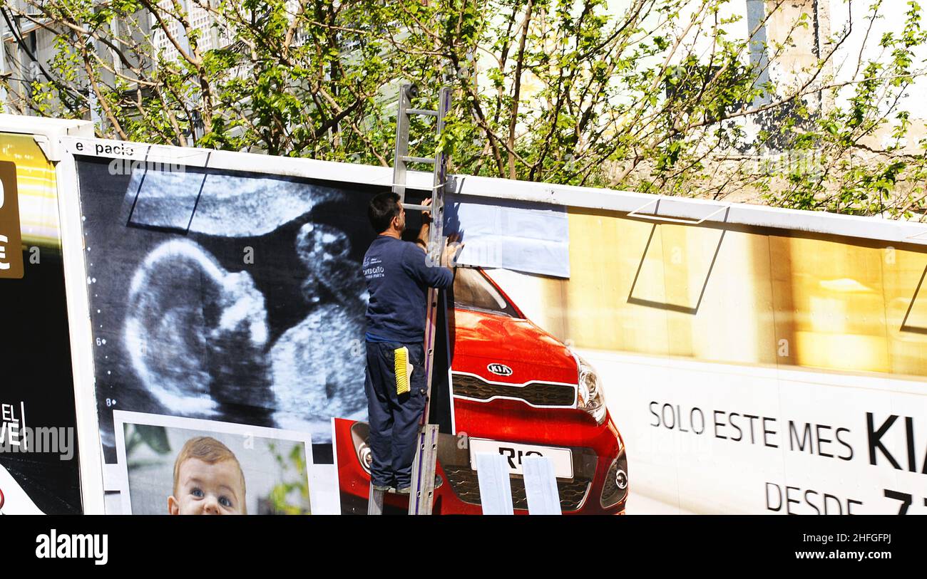 Man placing advertising poster on an advertising billboard in Barcelona ...