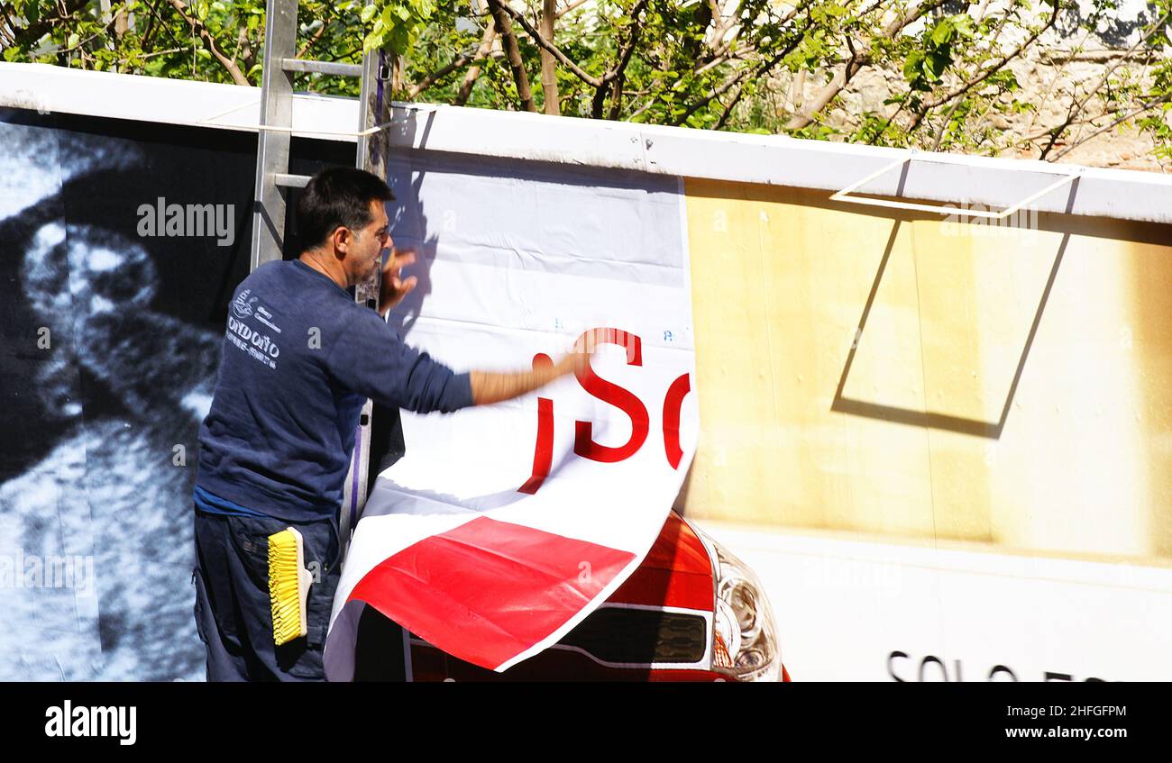 Man placing advertising poster on an advertising billboard in Barcelona ...