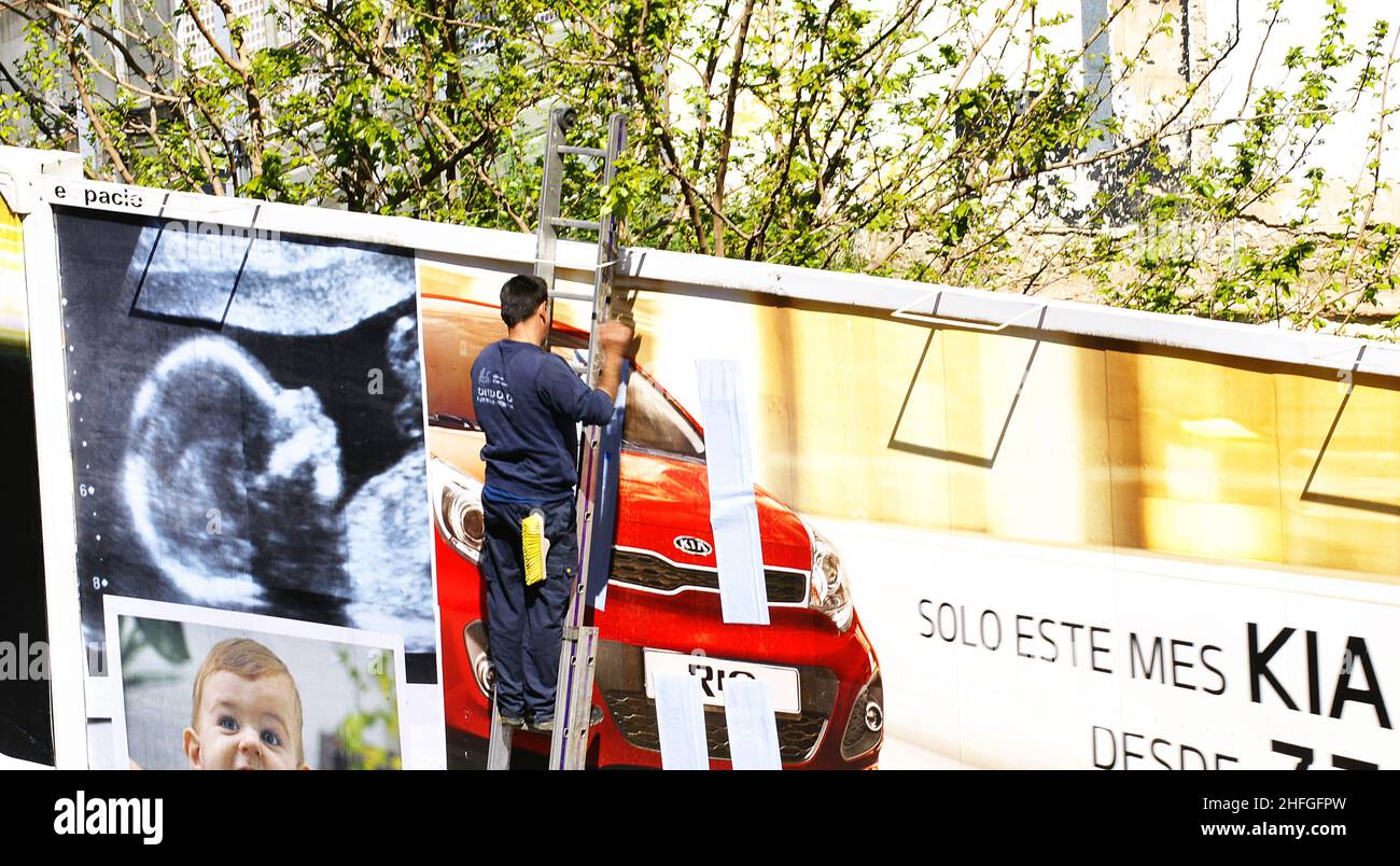 Man placing advertising poster on an advertising billboard in Barcelona ...