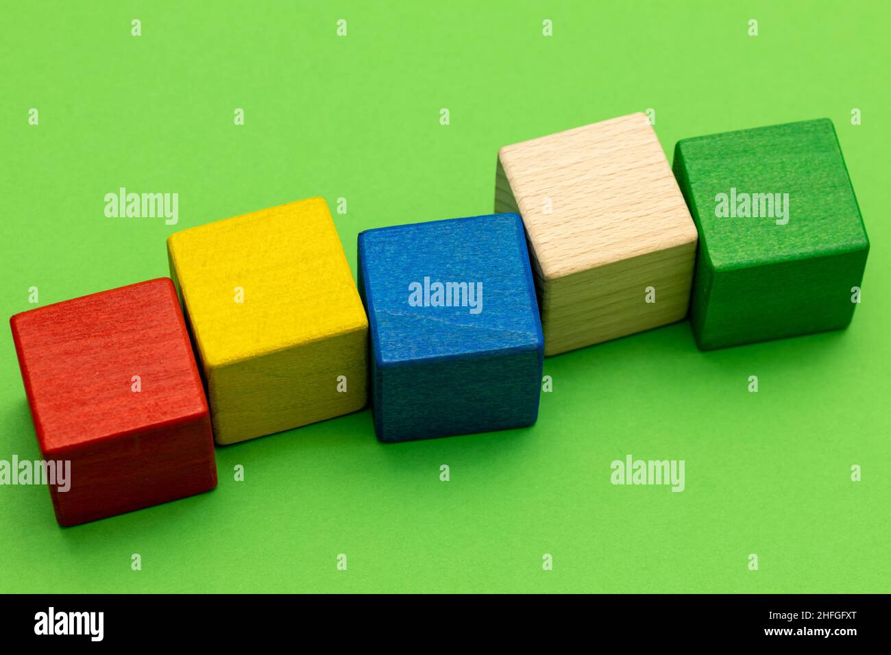 five colored wooden blocks on a green background, space for text ...