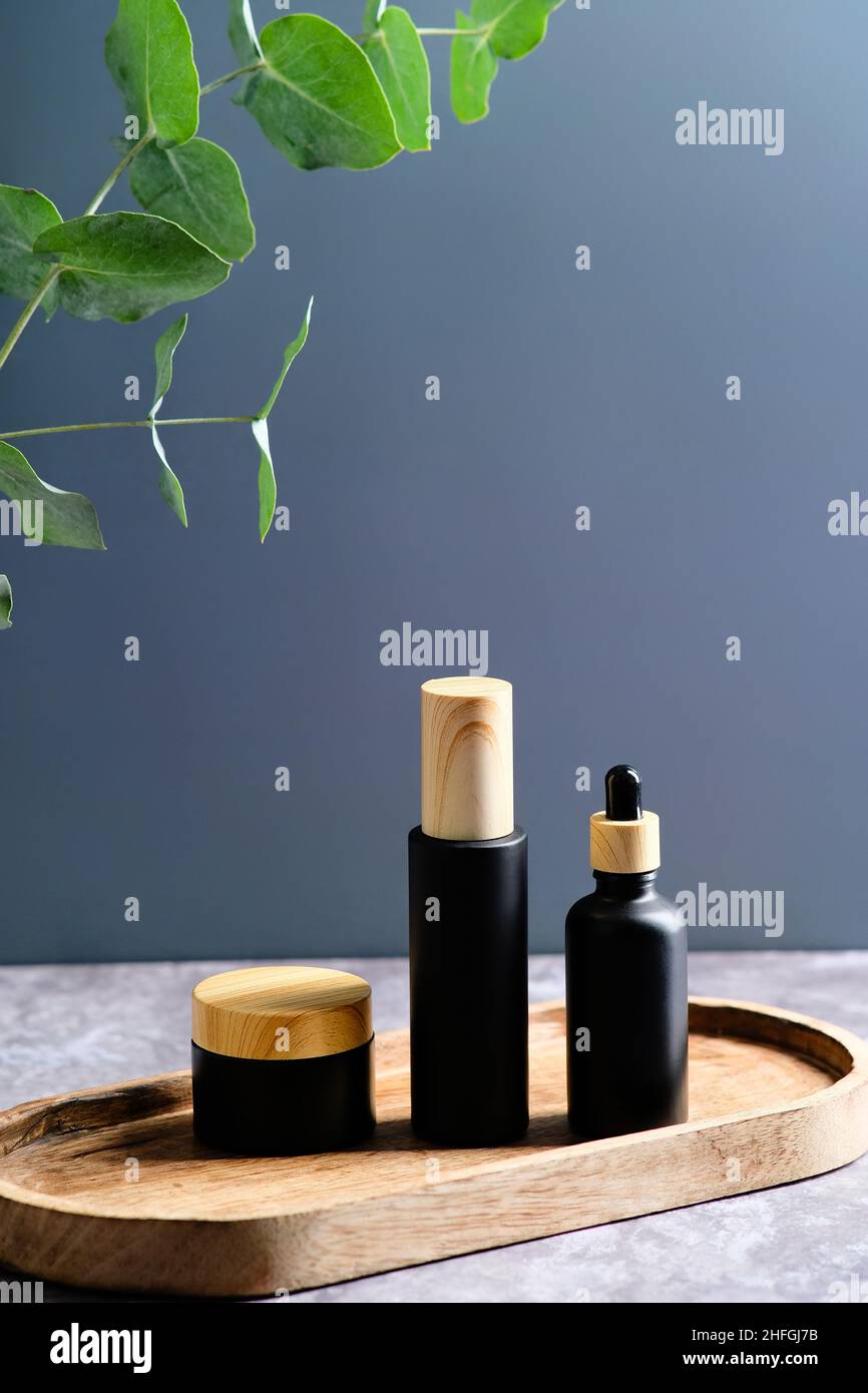 Black and wooden cosmetics containers set on dark blue background ...
