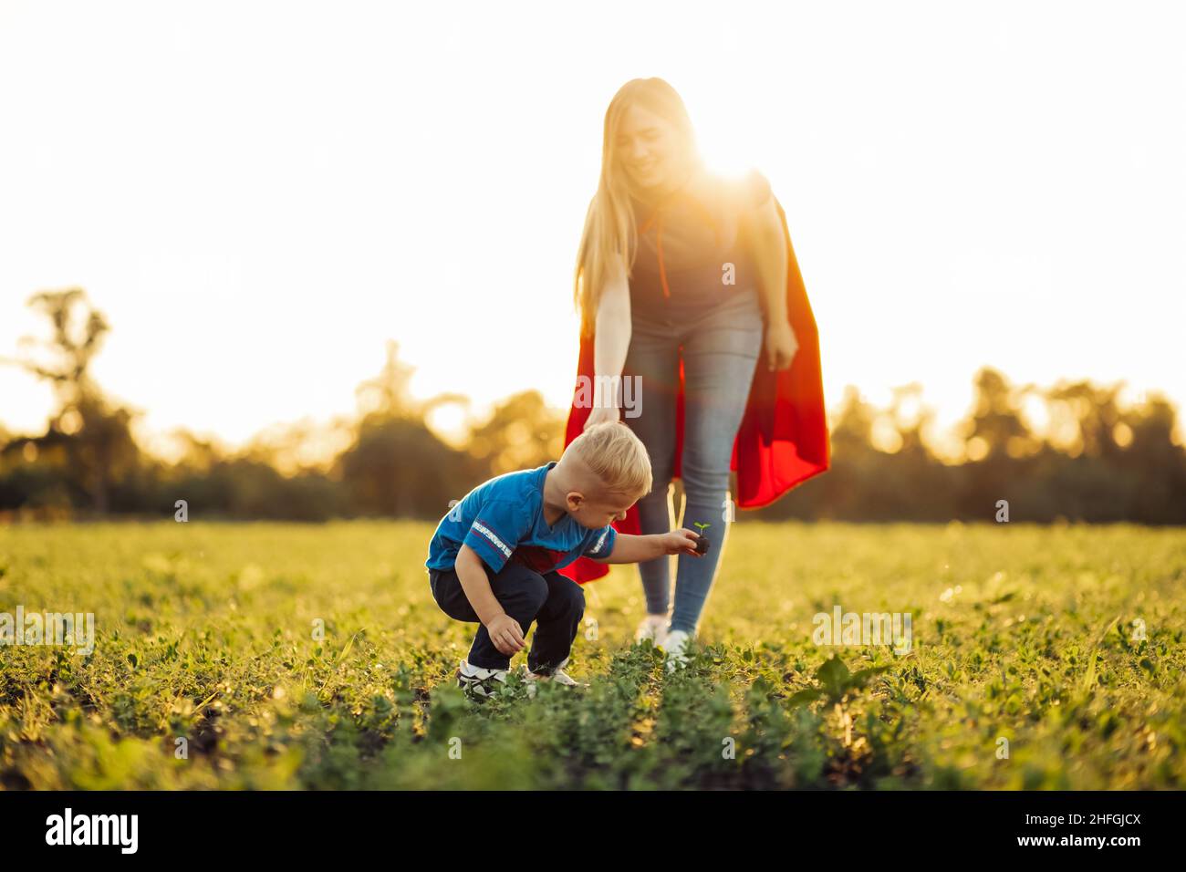 Happy family, Mom and her little son in superhero costumes, plant a ...