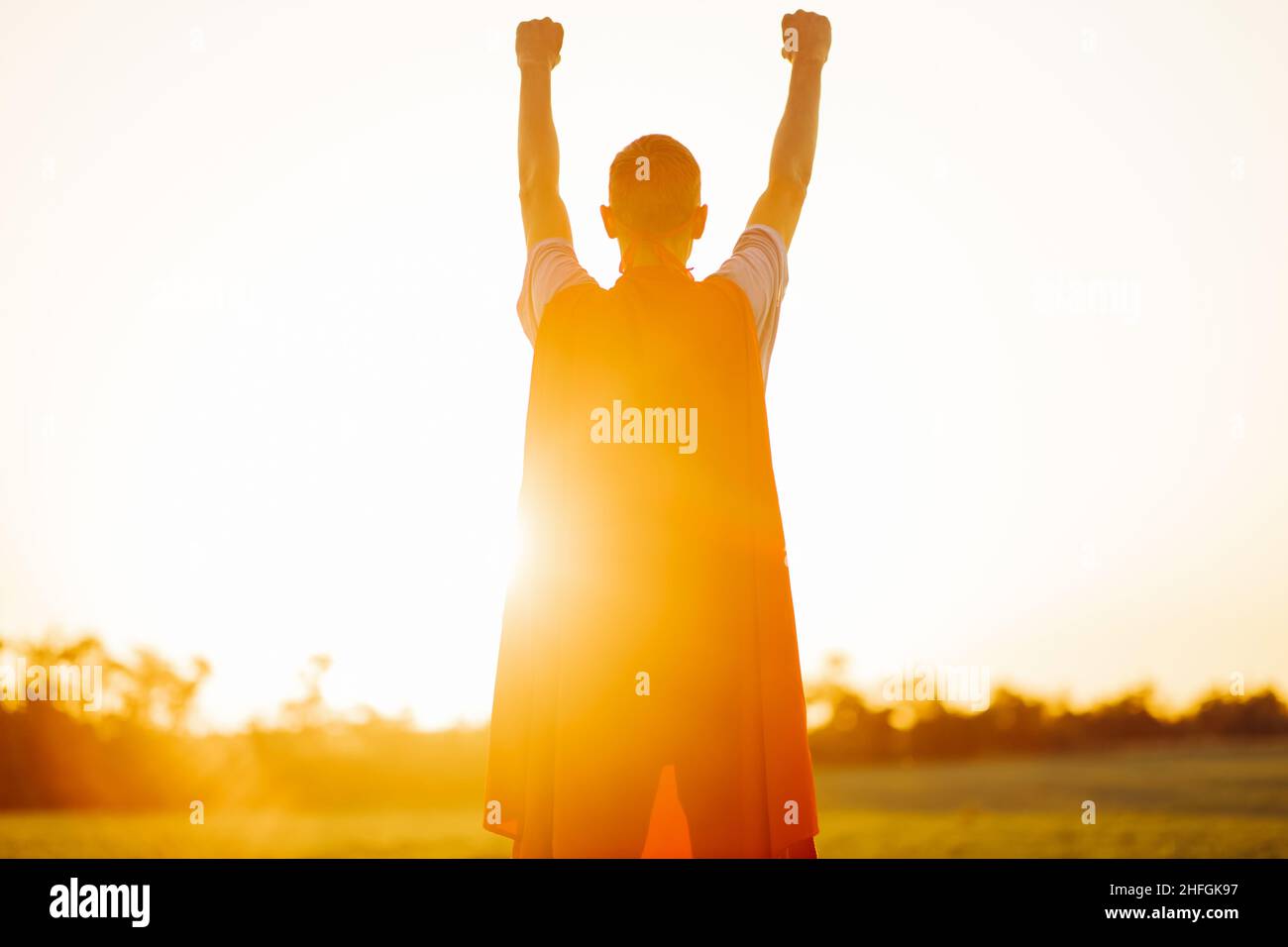 Rear view, Strong male hero wears superhero costume, raises hands ...