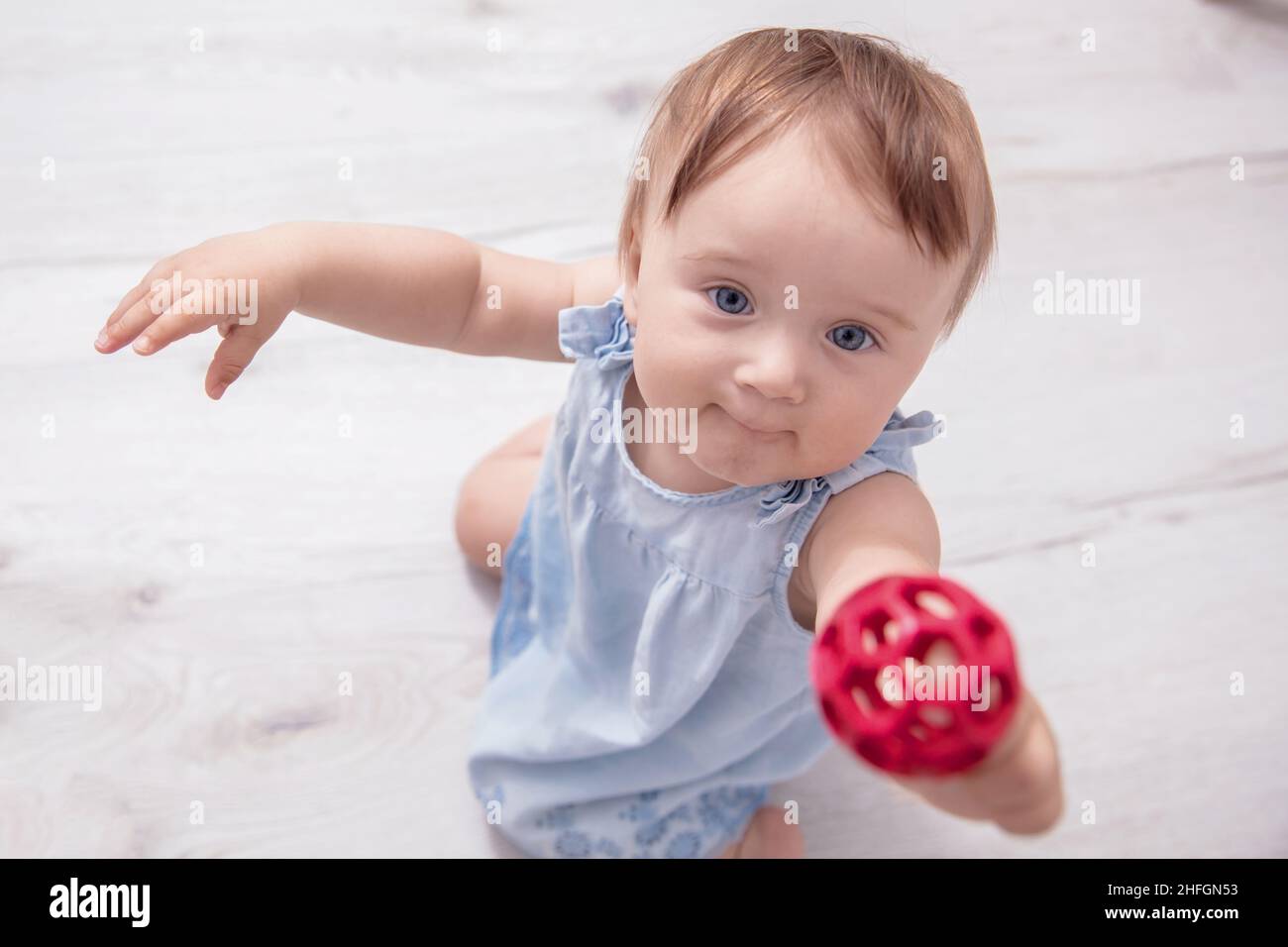 Infant baby girl in blue dress holds red ball. Top from the view Stock ...