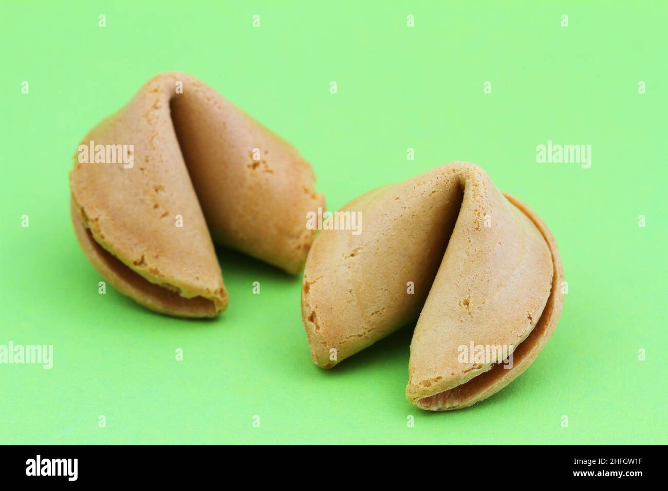 Two Chinese fortune cookies on bright green surface with copy space ...