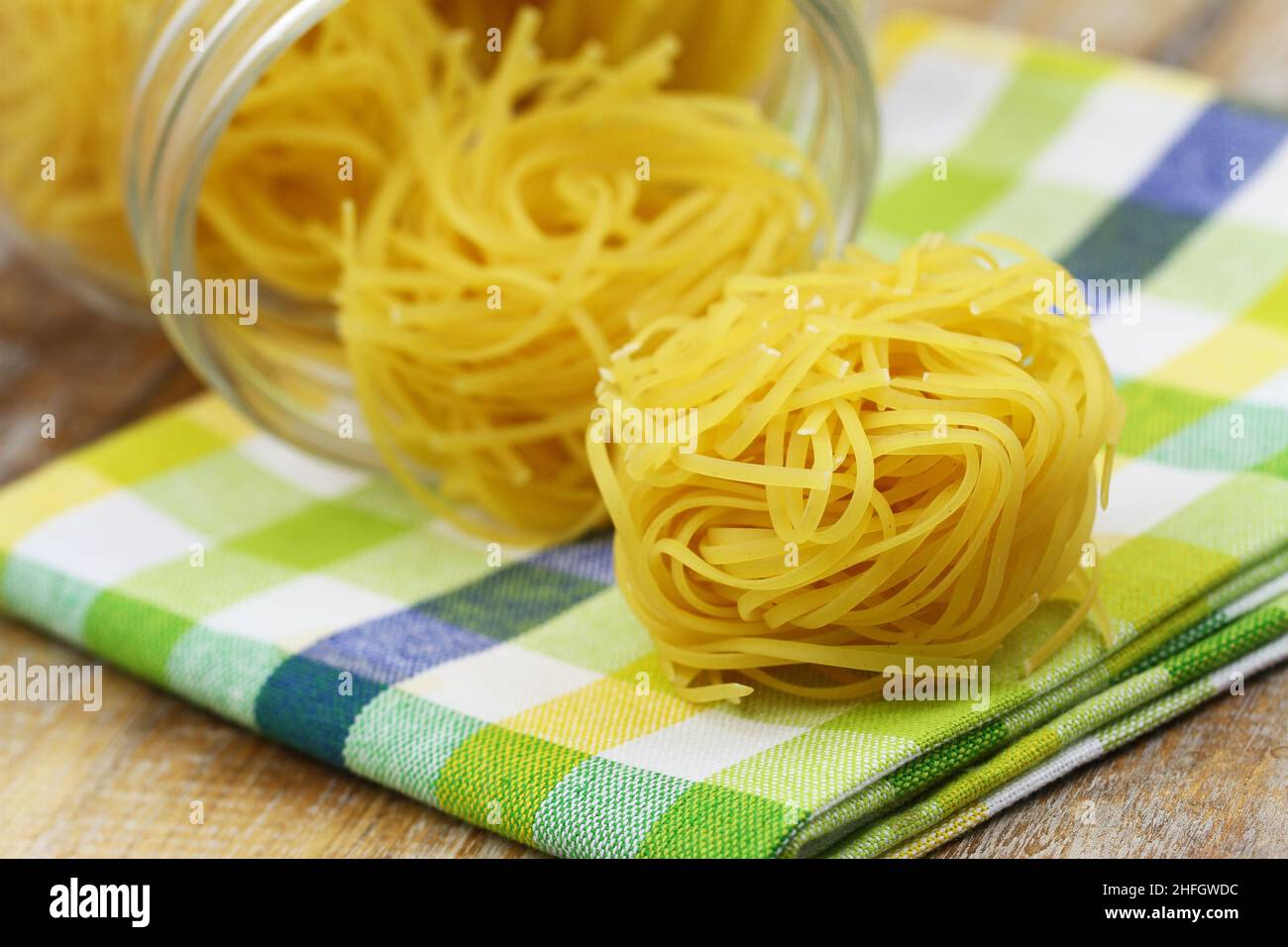 Uncooked Italian tagliatelle nests on colorful kitchen cloth, closeup ...