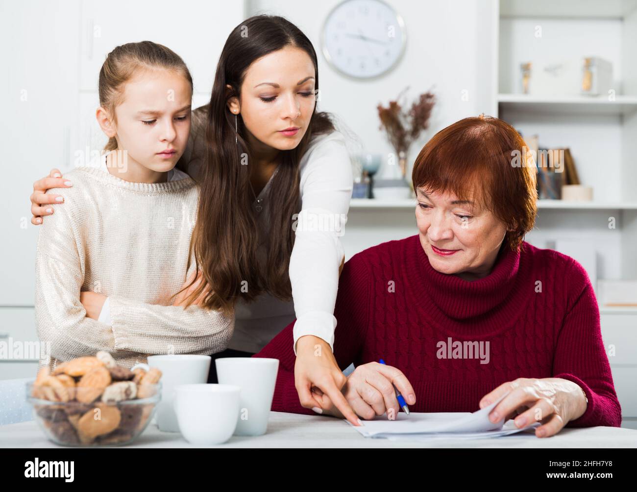 Adult daughter controlling signing of documents by grandmother Stock ...