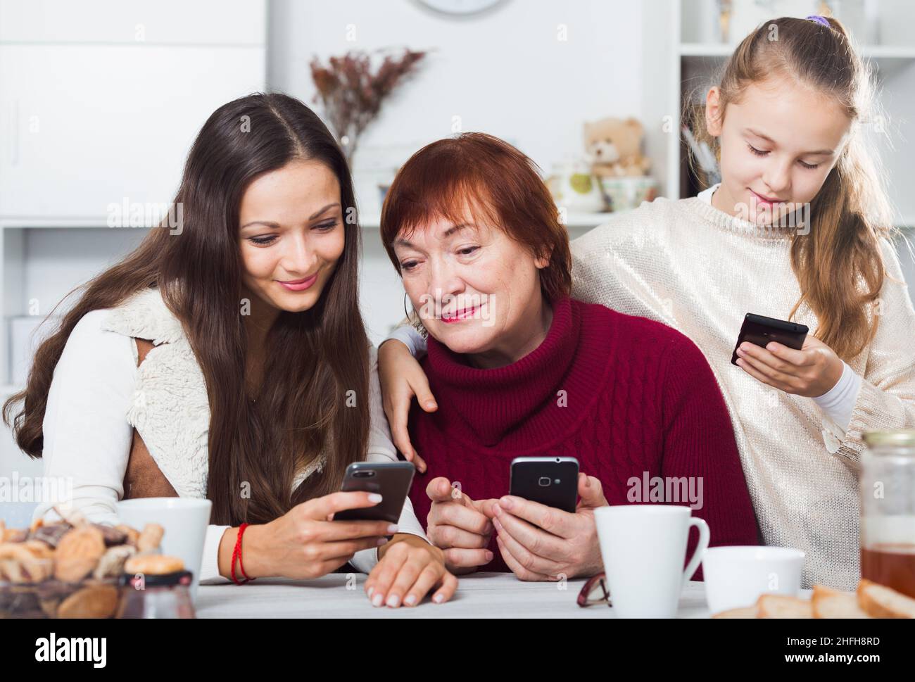 Three generations of family absorbedly looking at phones Stock Photo ...