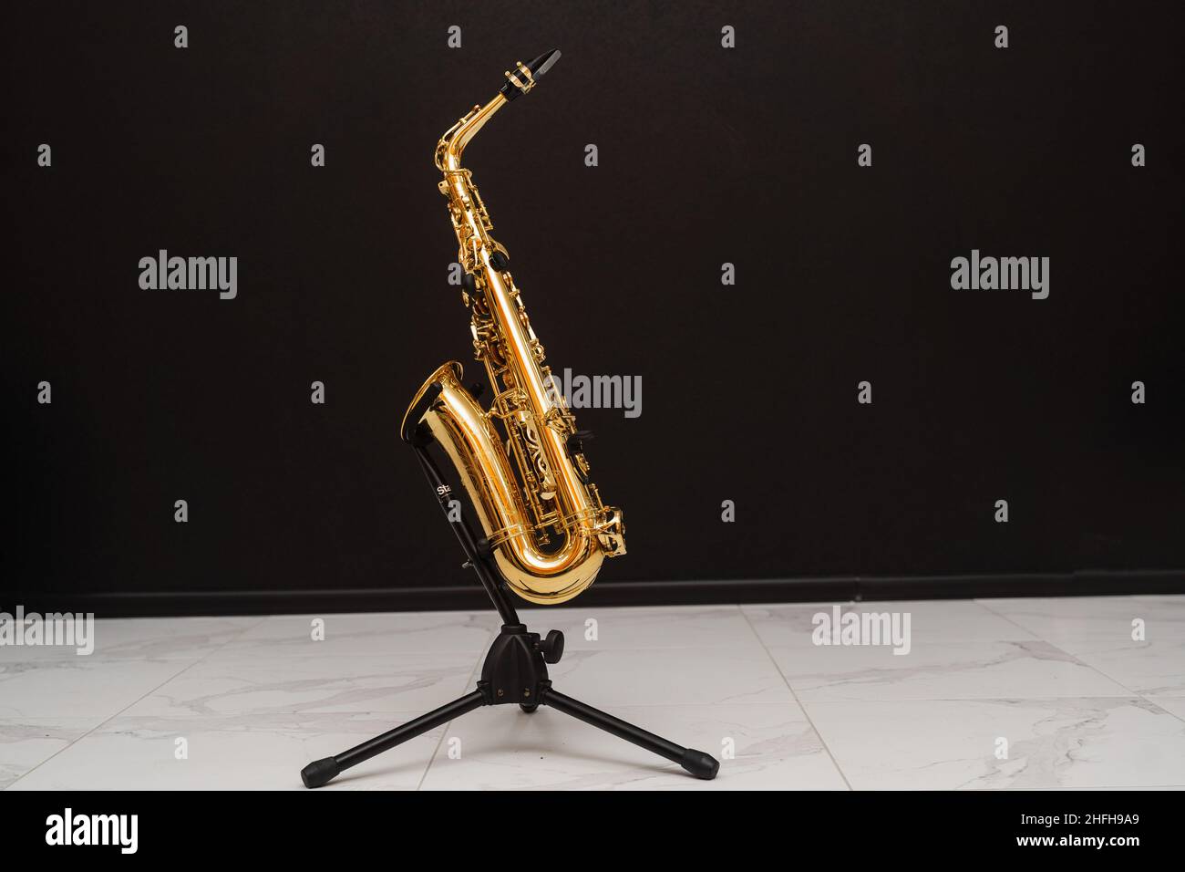 Saxophone musician instrument on stand on black background. Sax musical ...