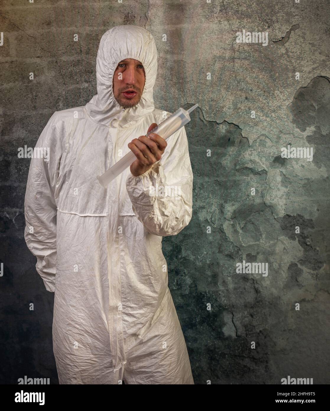 Man with white protection suit and big shot injection near old brick ...