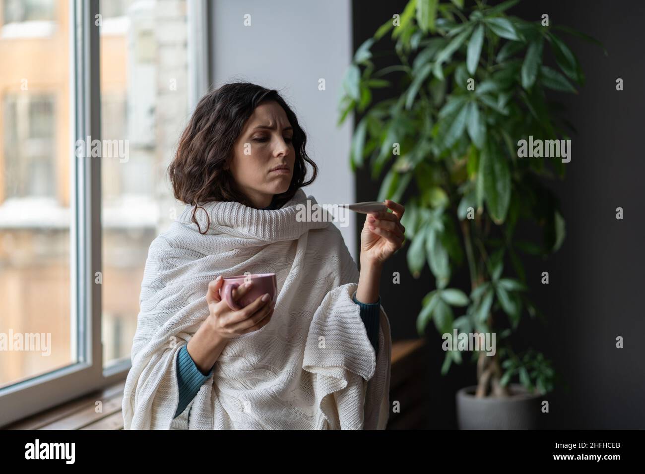 Sick unhealthy young woman with high fever looking at thermometer ...