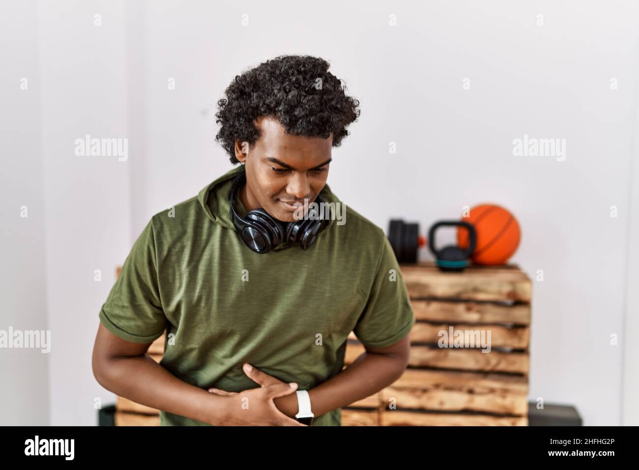 African man with curly hair wearing sportswear at the gym with hand on ...