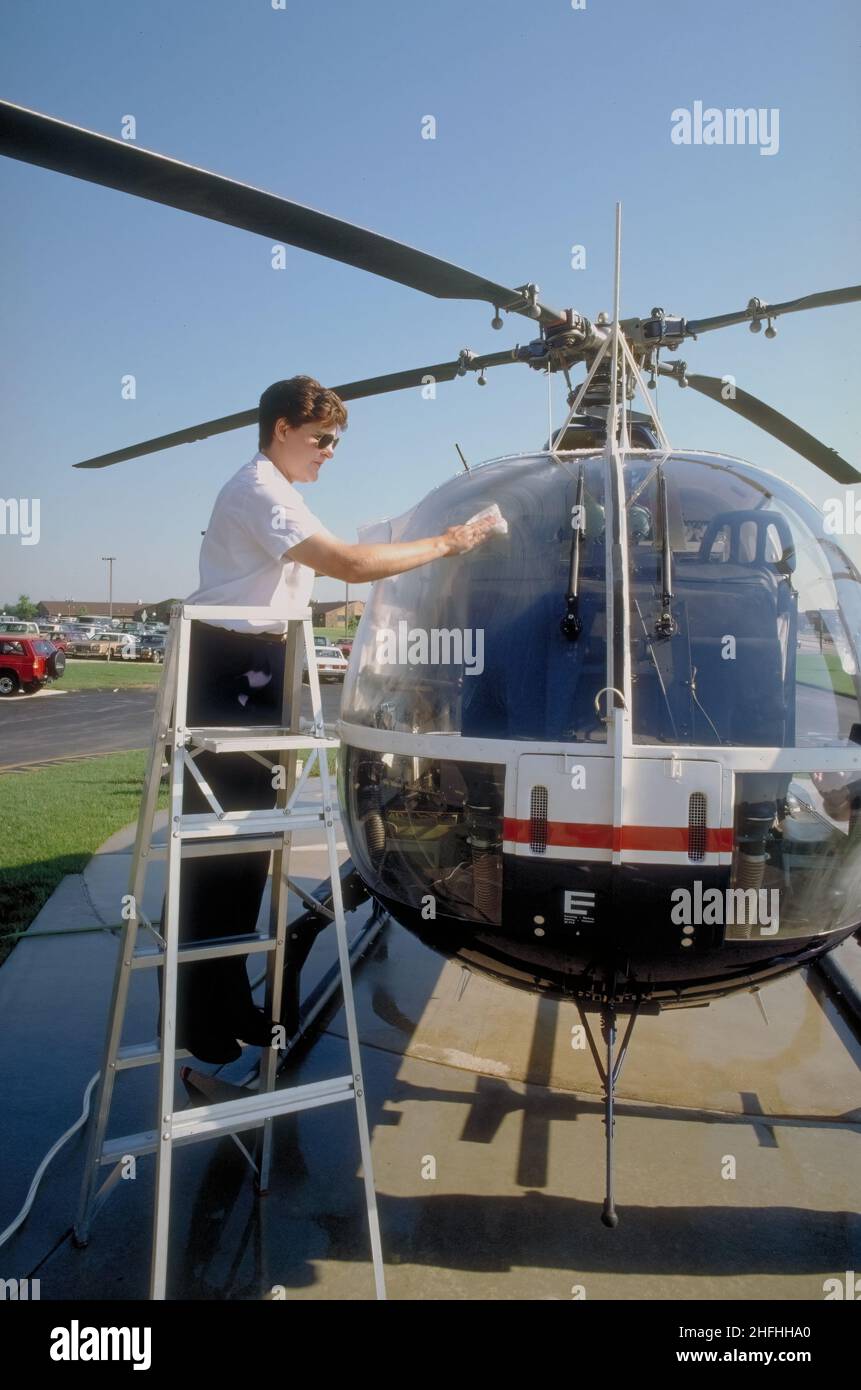 A female helicopter ambulance pilot cleans the aircraft's windscreen ...
