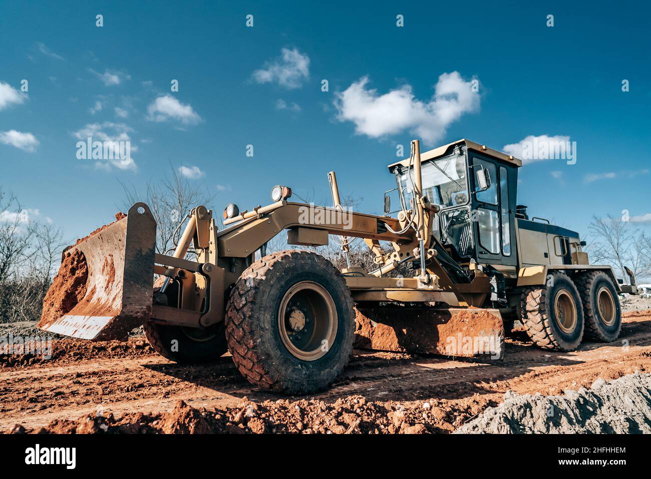 Road grader smoothing gravel surface for new road. Scraper leveling ...