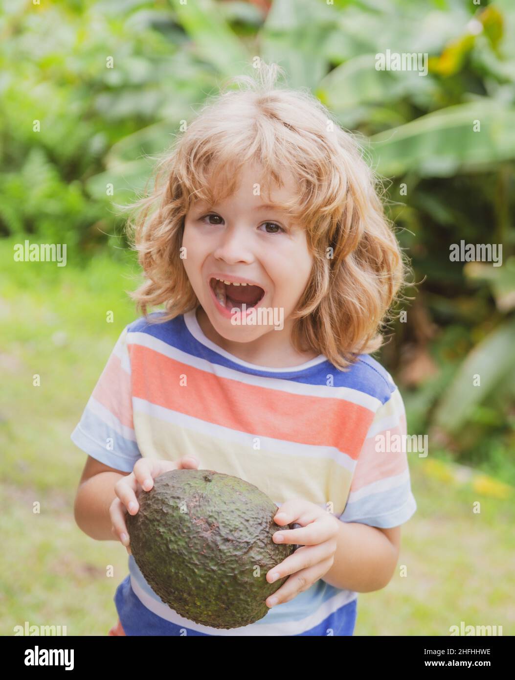 Kid eating and enjoying an avocado on a nature background. Healthy food ...