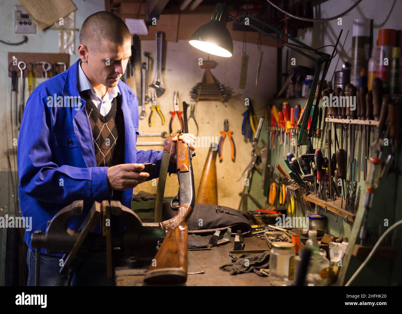 Gunsmith examines an automatic rifle before being repaired in weapons ...