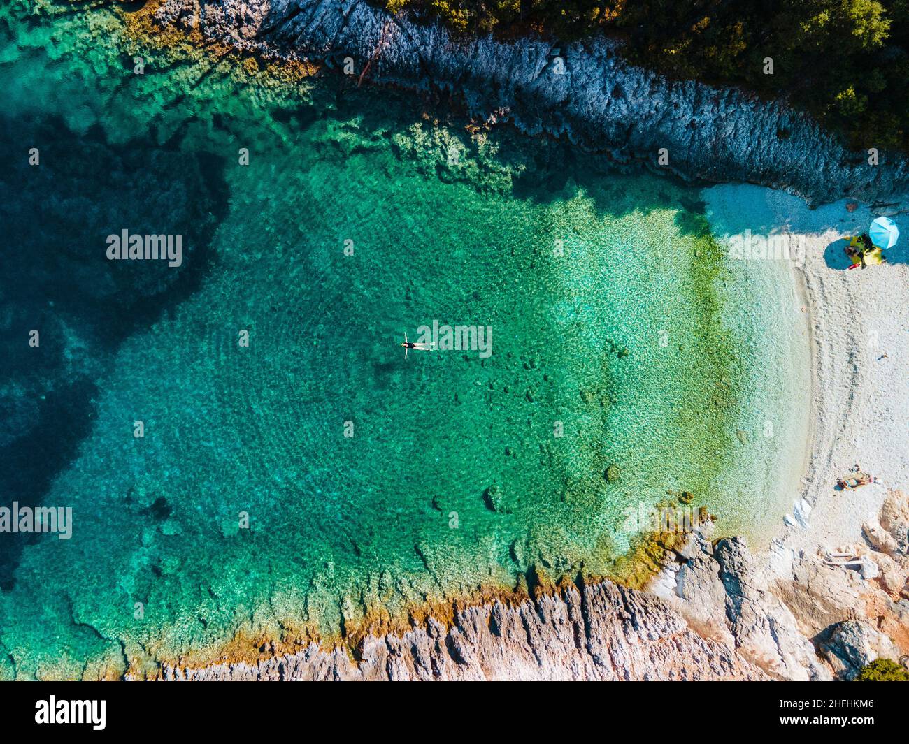 overhead view of woman floating on back in clear sea water greece ...