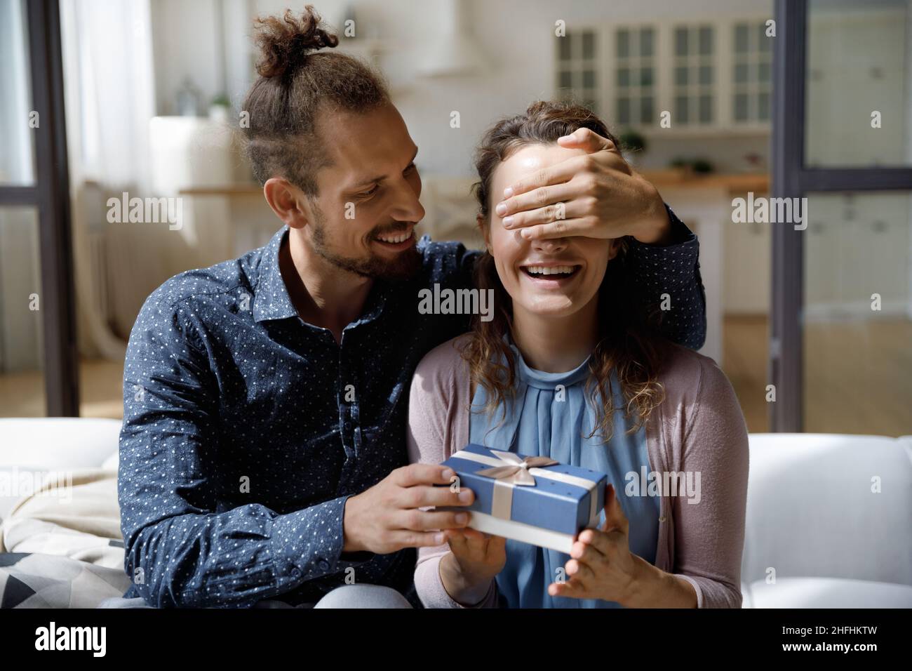 Smiling millennial man giving gift box to curious laughing woman Stock ...