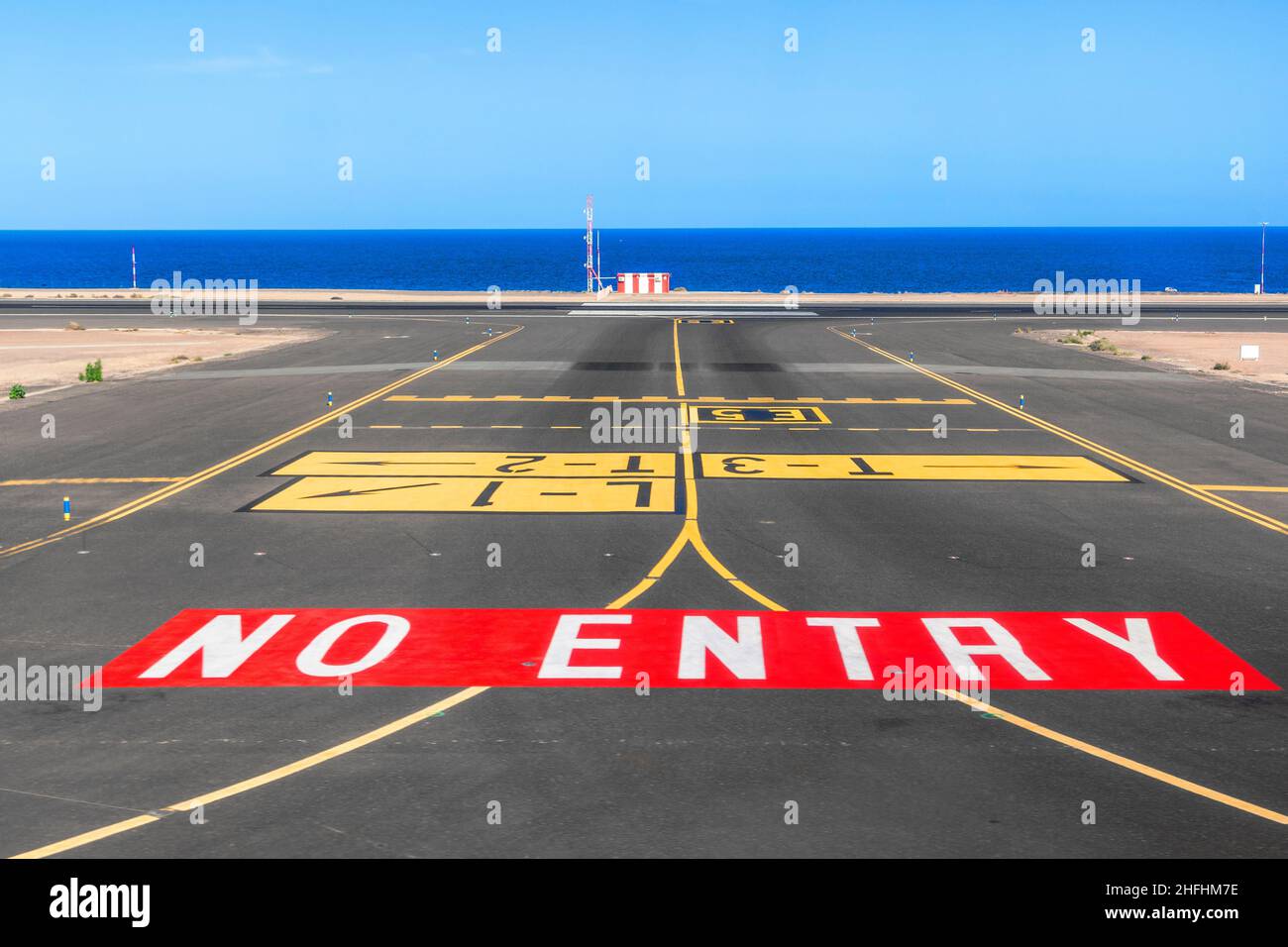no entry sign at the runway of the airport with ocean in background ...