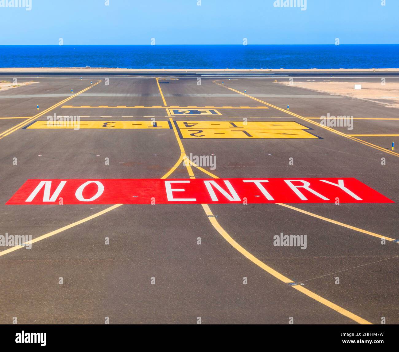 no entry sign at the runway of the airport with ocean in background ...