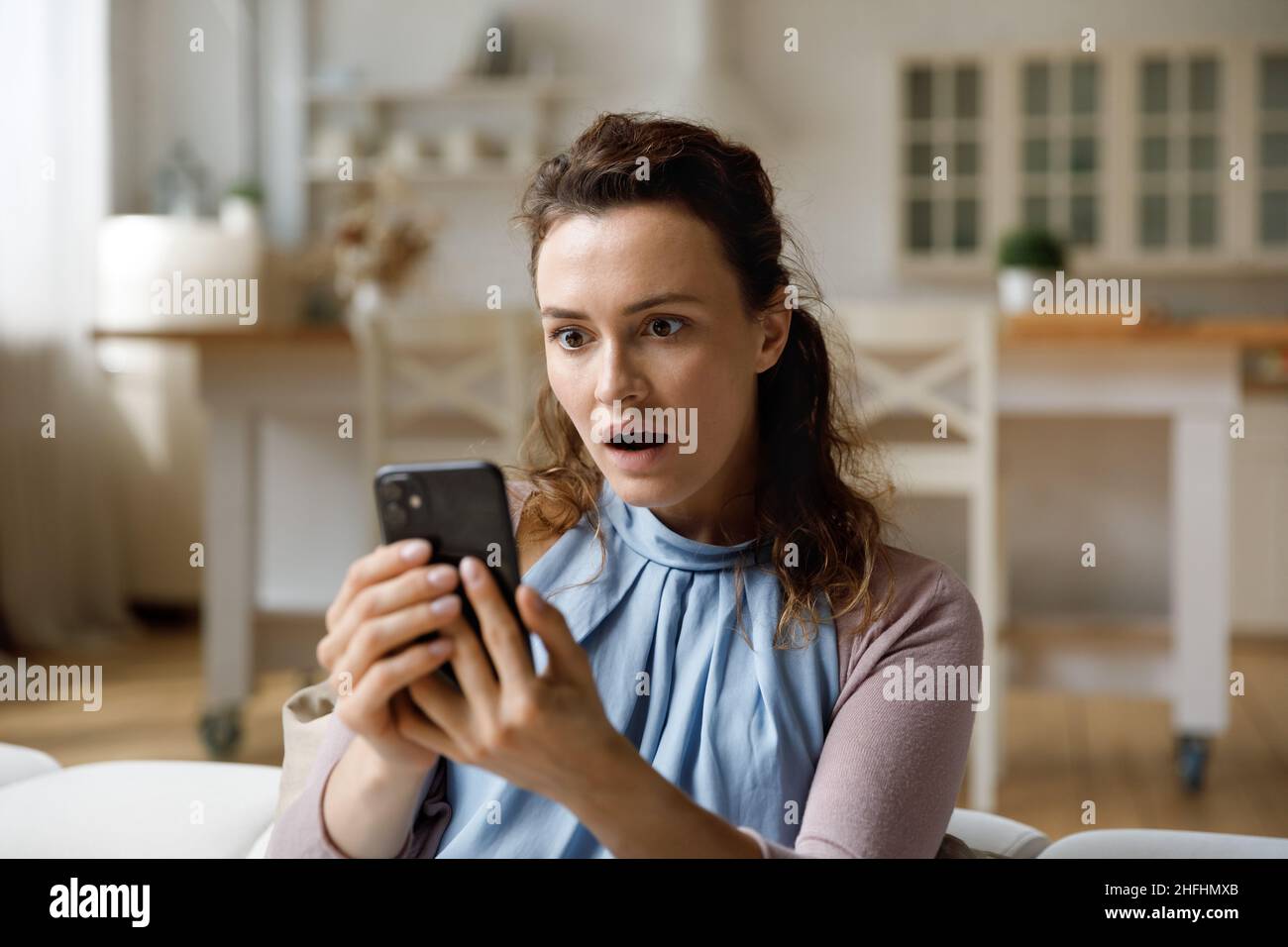 Shocked young woman looking at smartphone screen Stock Photo - Alamy