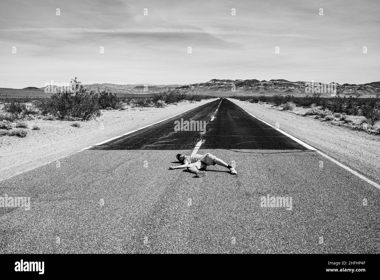 A man laying motionless in the middle of a highway in the Death Valley ...