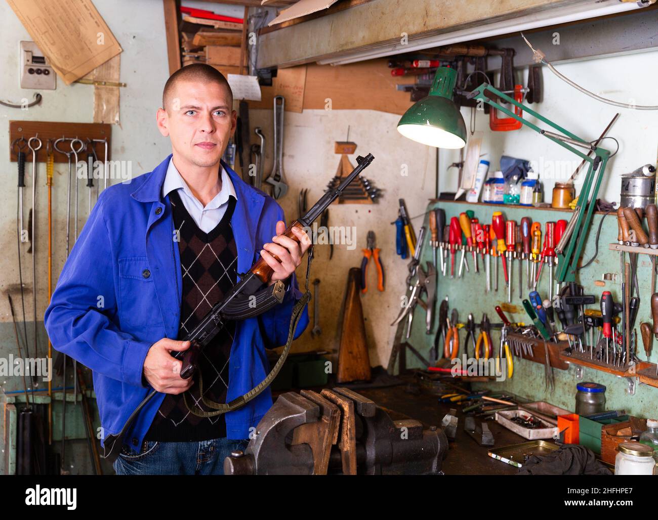 Gunsmith with Kalashnikov assault rifle in weapons workshop Stock Photo ...