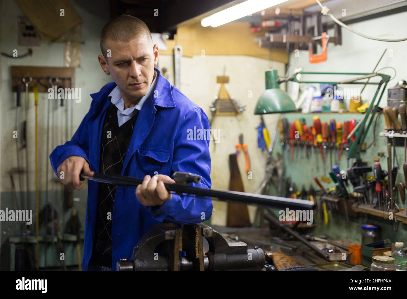 Gun repairman cleaning shotgun barrel before assembly in workshop Stock ...