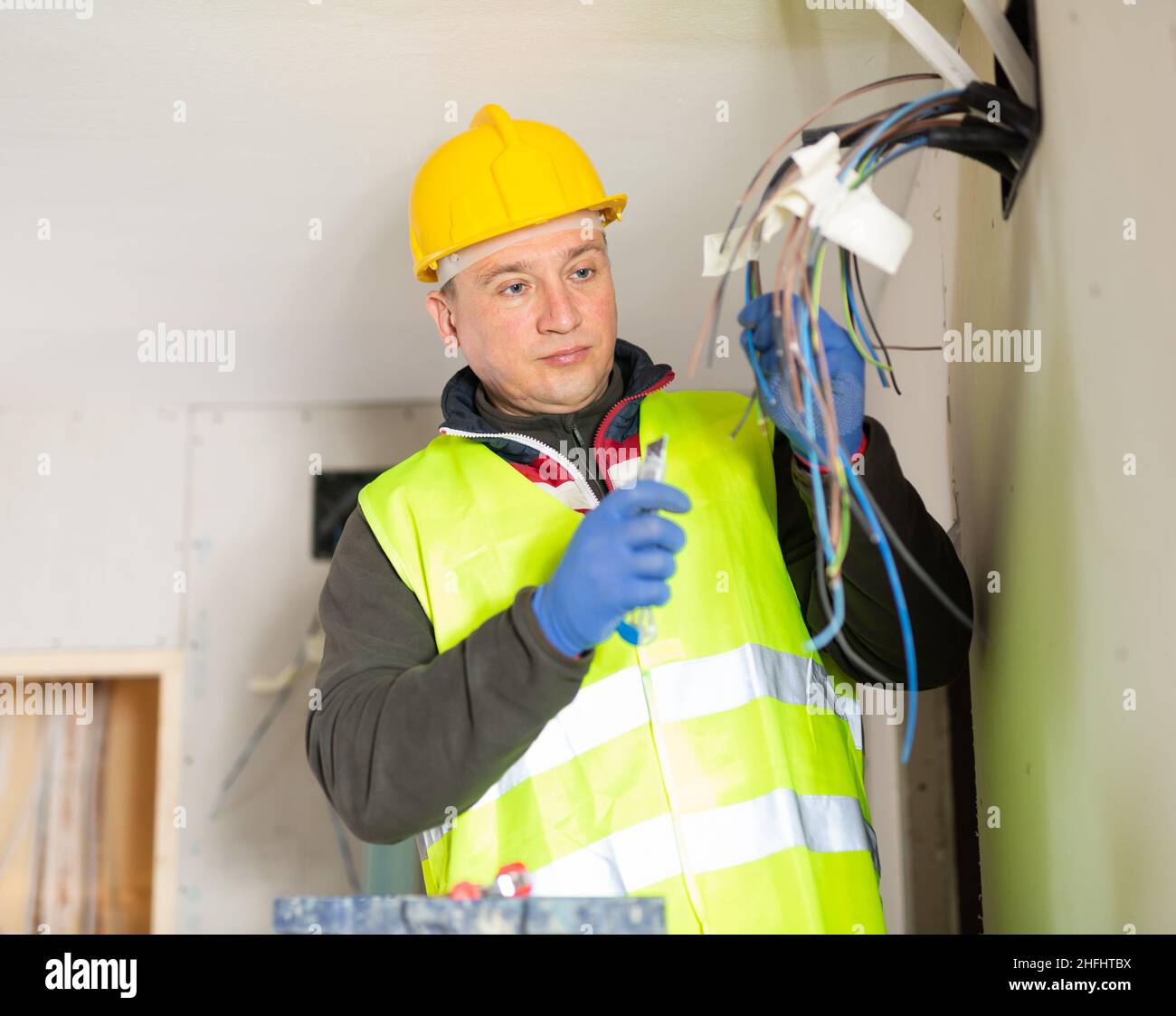 Electrician mounting electrical wiring inside building in process of ...