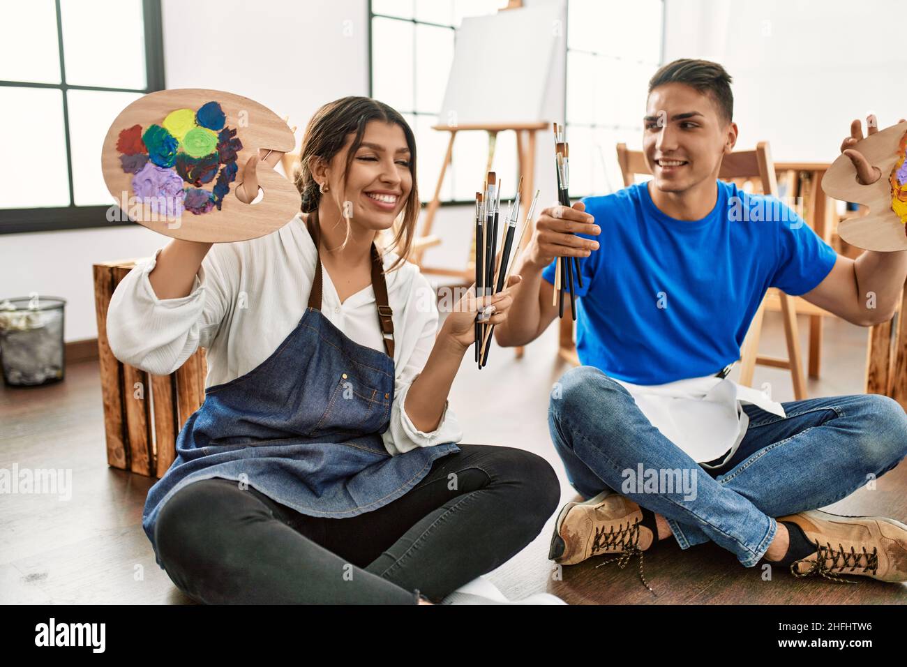 Two students smiling happy painting at art school Stock Photo - Alamy