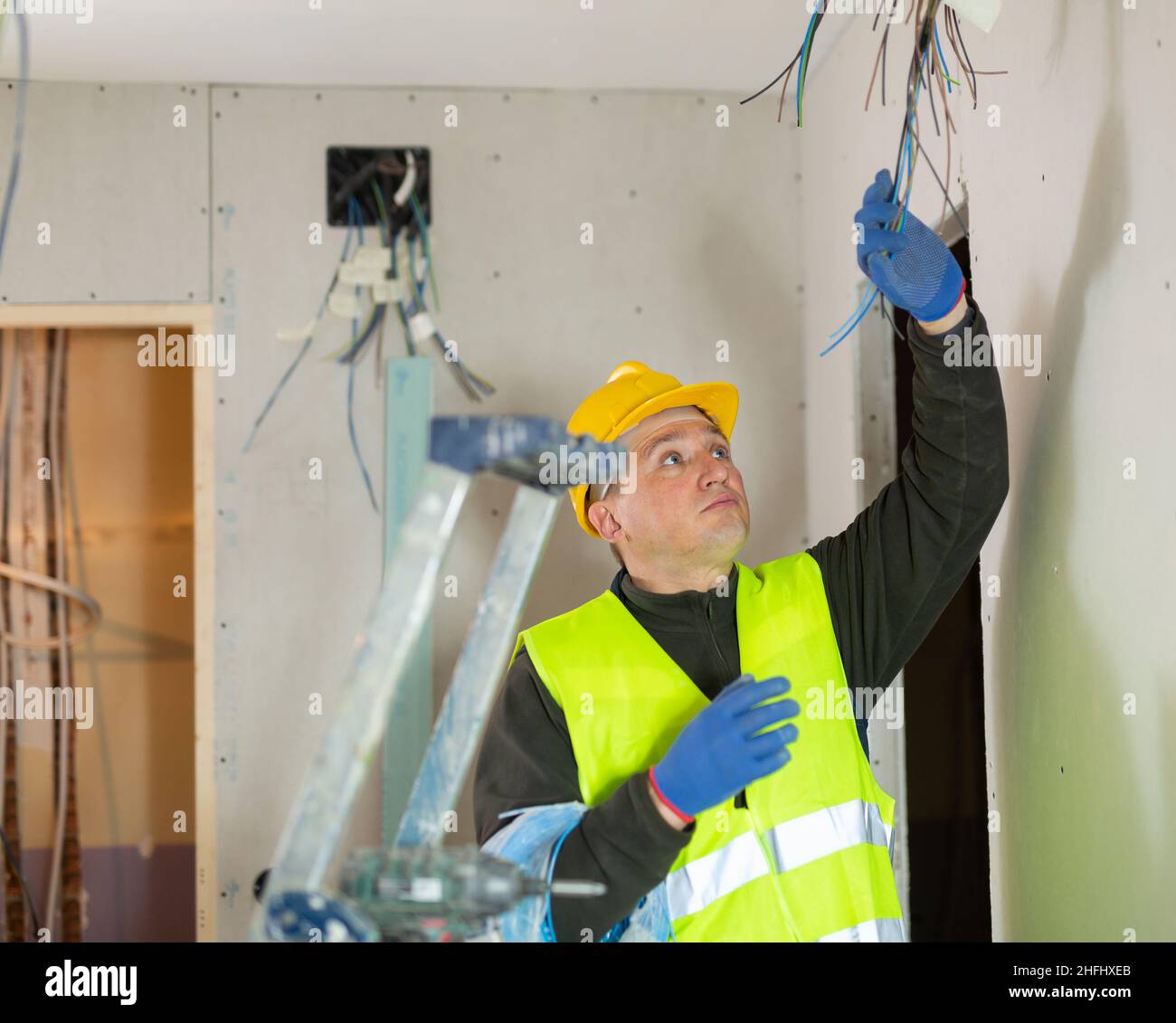Worker repairing wires while installing electricity Stock Photo - Alamy