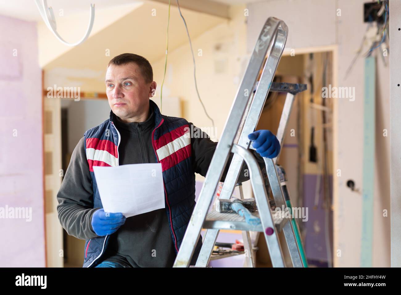 Repair man standing in apartment and checking documentation Stock Photo ...