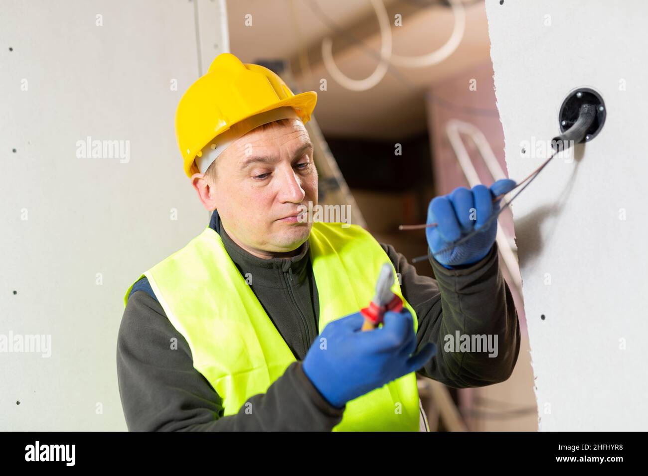 Experienced electrician laying electric wires in building under ...