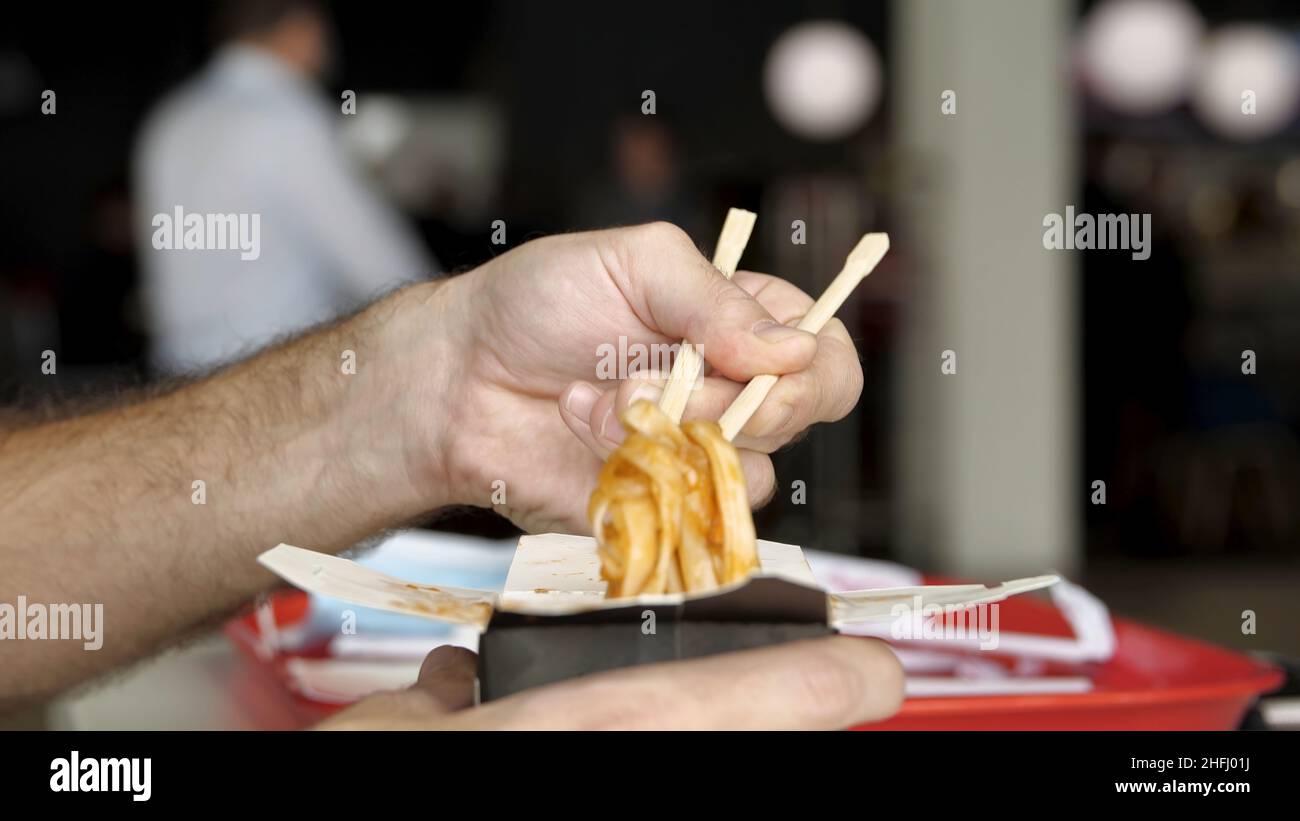 Close up of male hands with wooden chinese chopsticks eating delicious ...