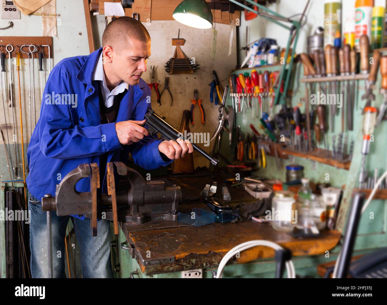 Skilled craftsman of weapons workshop repairing of small-bore handgun ...