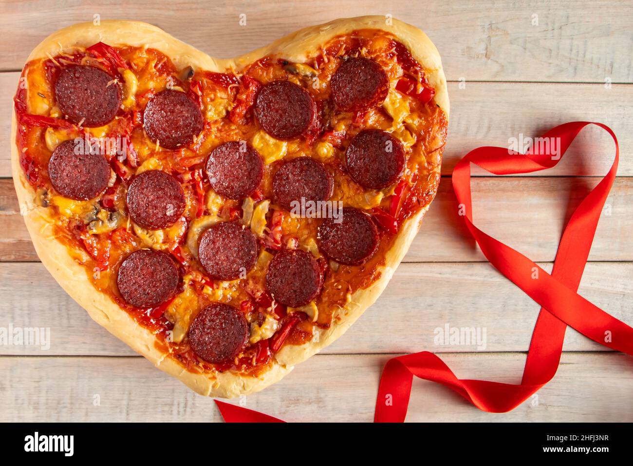 Heart shaped pepperoni pizza on a wooden background. Valentines day ...