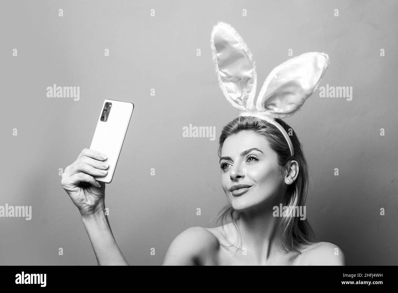 Easter bunny woman with rabbit ears having call holding smart phone in ...