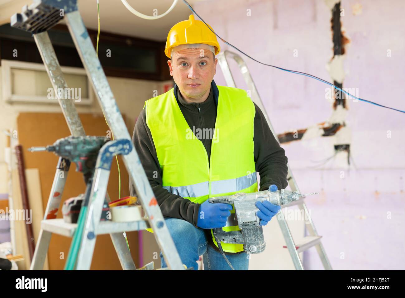 Repair man with drill standing in apartment Stock Photo - Alamy