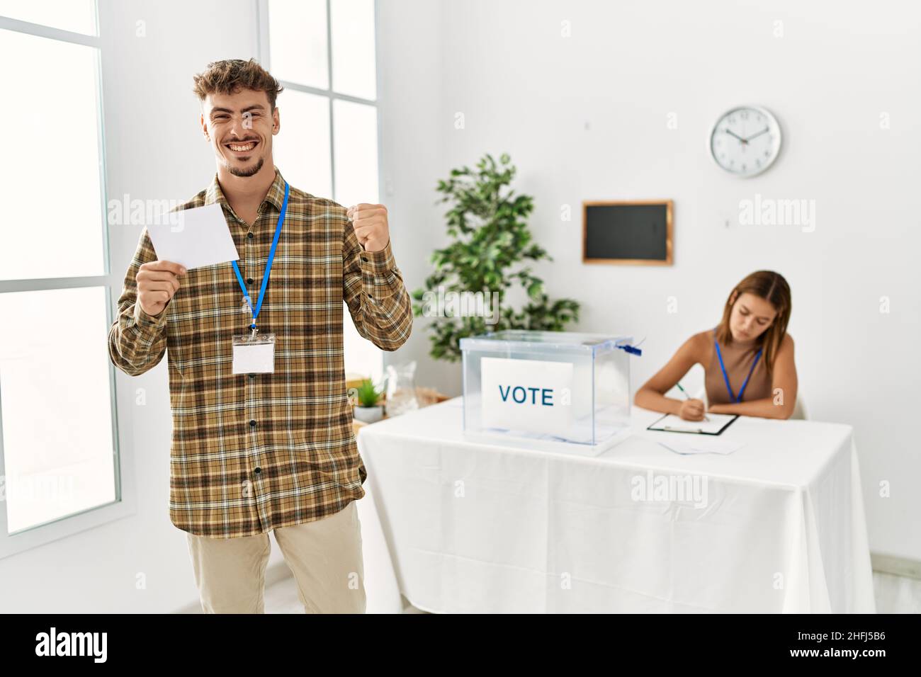 Young handsome man voting putting envelop in ballot box screaming proud ...