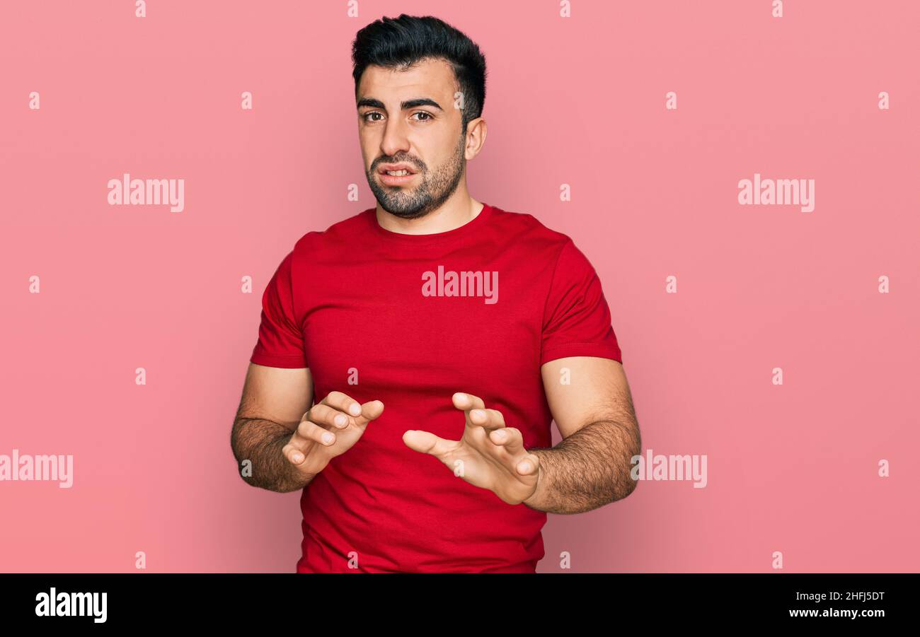 Hispanic man with beard wearing casual red t shirt disgusted expression ...