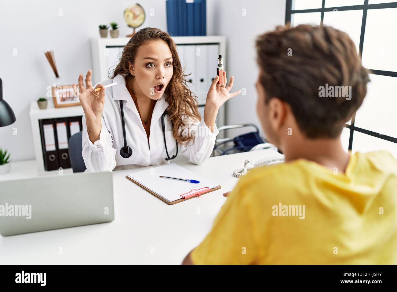 Young doctor woman showing electronic cigarette and normal cigarrete to ...