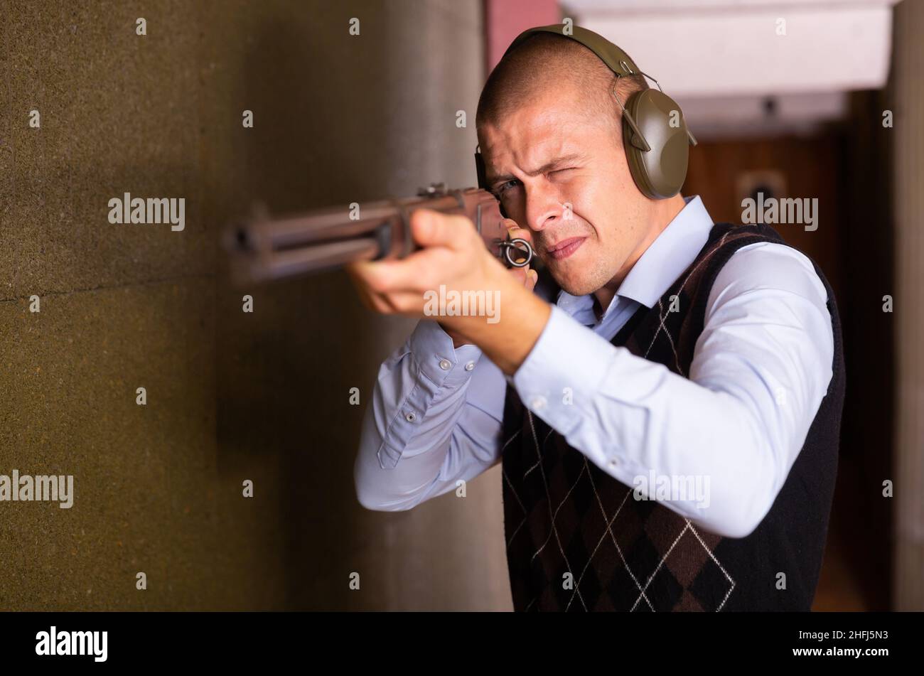 Focused man aiming shotgun at target in shooting range Stock Photo - Alamy