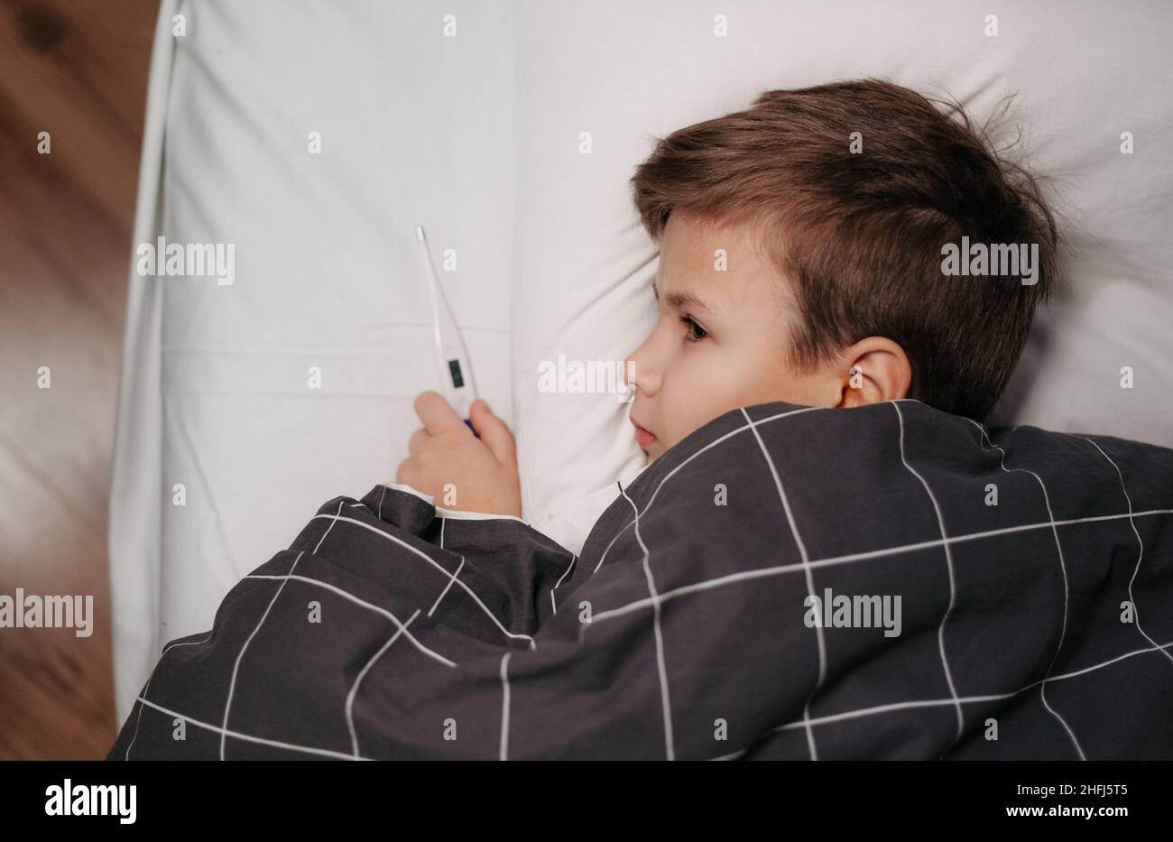 Sick child laying in bed and holding termometer Stock Photo - Alamy