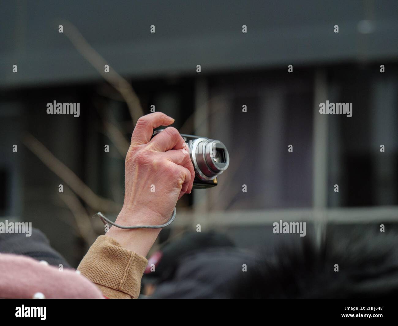 Hand holding point & shoot digital camera above crowd Stock Photo - Alamy