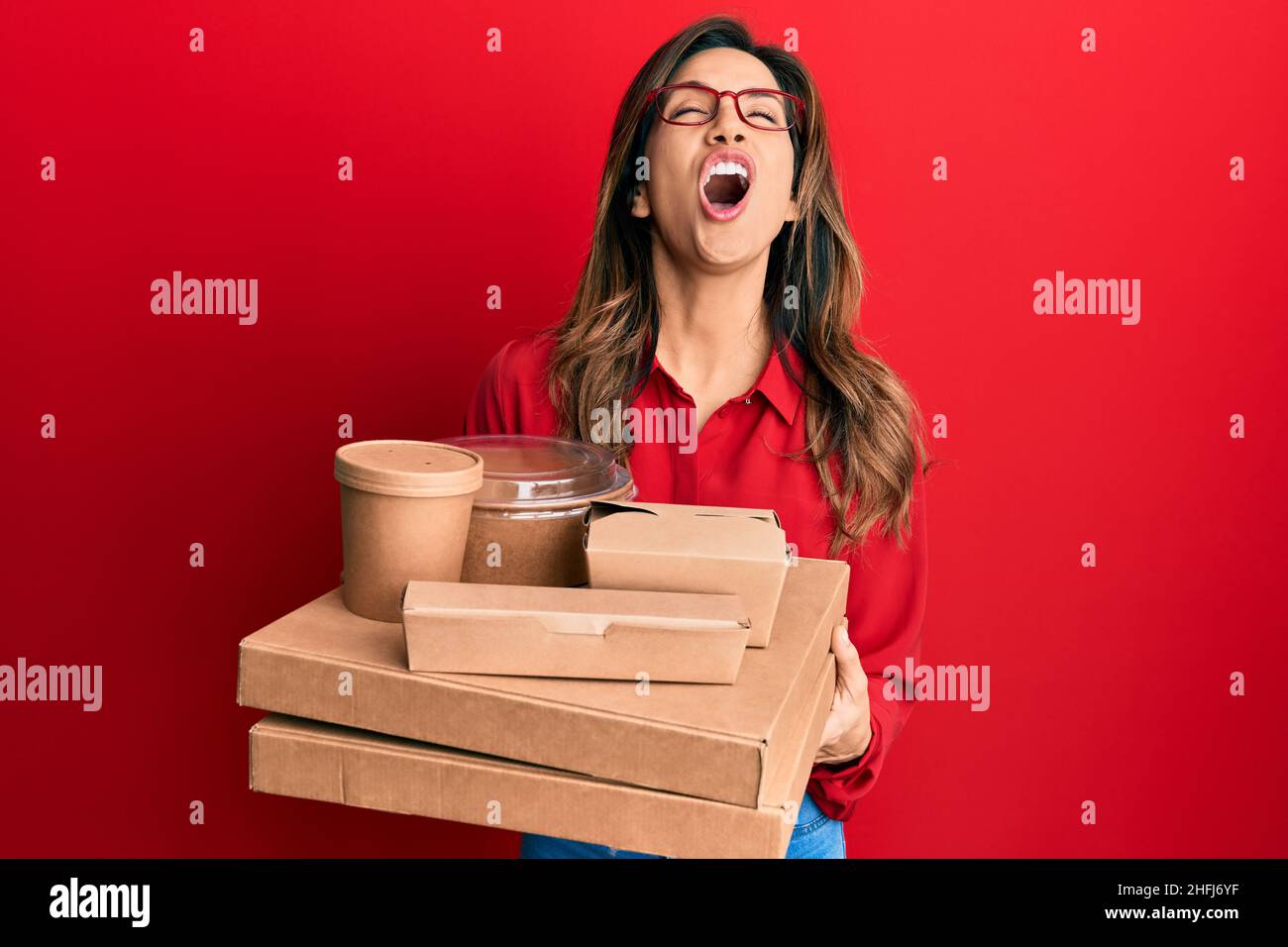 Young latin woman holding take away food angry and mad screaming ...