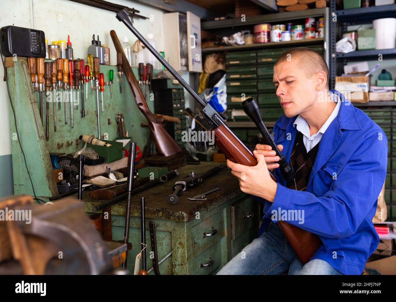 Gunsmith attaches a telescopic sight to rifle in weapons workshop Stock ...