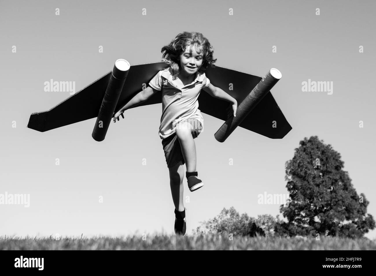 Happy child running with paper wings jumping against blue sky. Portrait ...