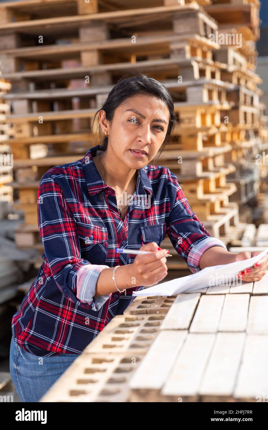Woman manager keeps records of building materials in the open area of ...